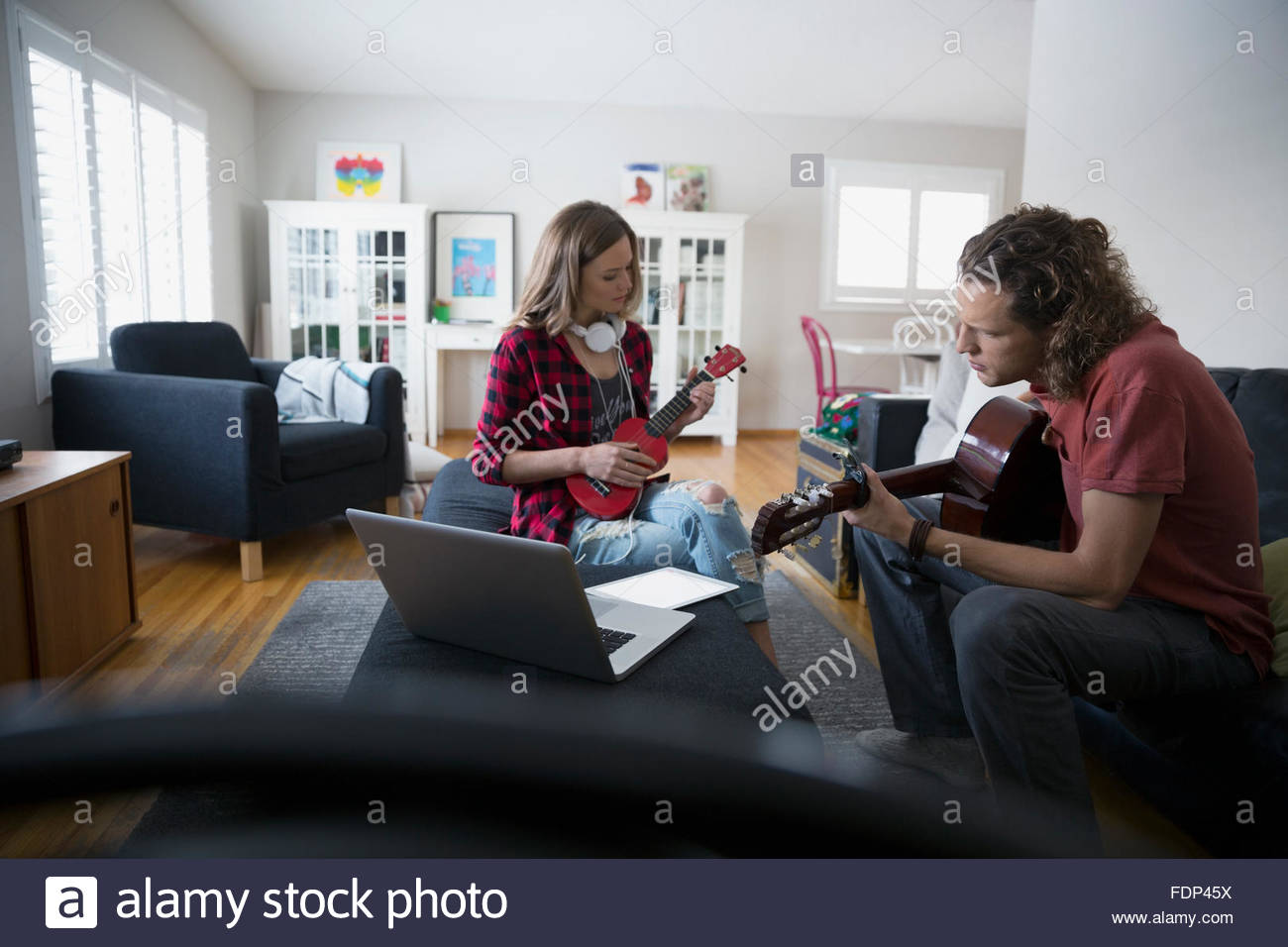 Couple playing guitar and ukulele in living room Stock Photo - Alamy