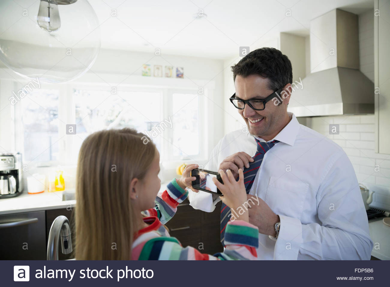 Daughter photographing father with camera phone in kitchen Stock Photo ...