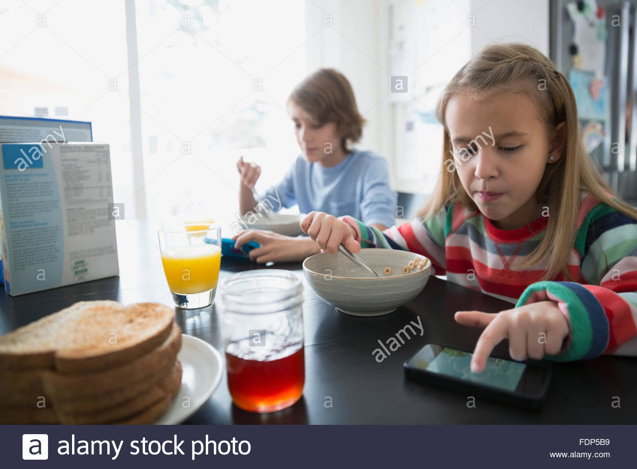 Brother sister eating breakfast texting hi-res stock photography and ...