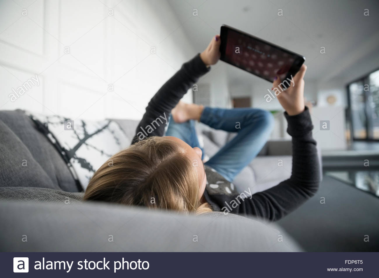 Girl using digital tablet laying on sofa Stock Photo - Alamy
