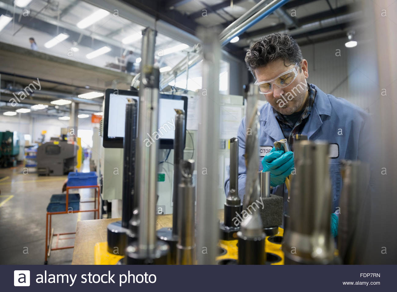 Worker examining machine part in factory Stock Photo - Alamy