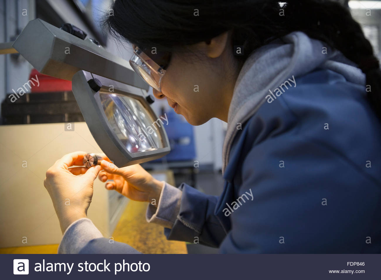 Worker using magnification glass to examine part factory Stock Photo ...