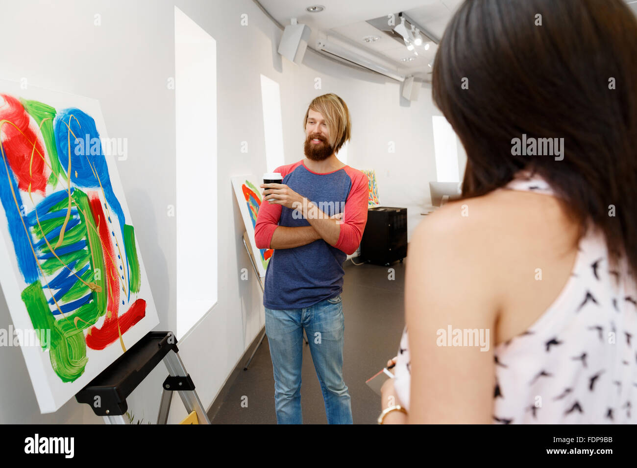 Young people standing in a gallery and contemplating abstract artwork ...