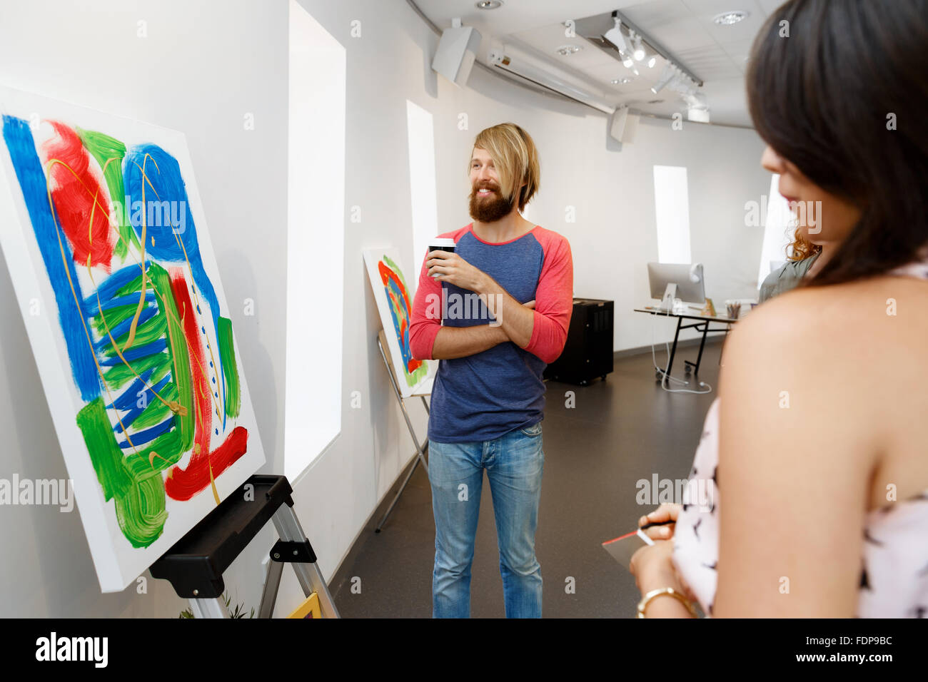 Young people standing in a gallery and contemplating abstract artwork ...