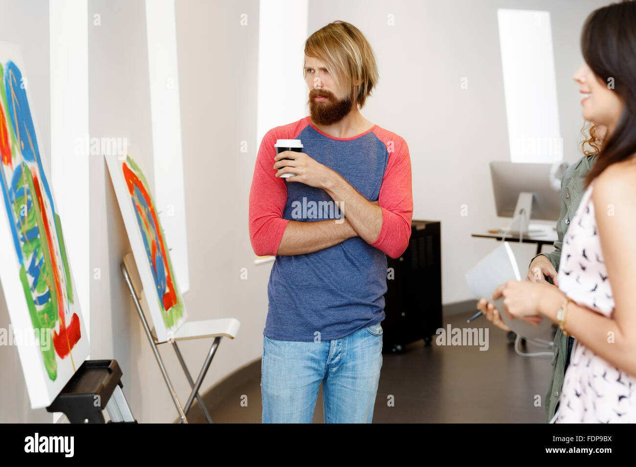 Young people standing in a gallery and contemplating abstract artwork ...