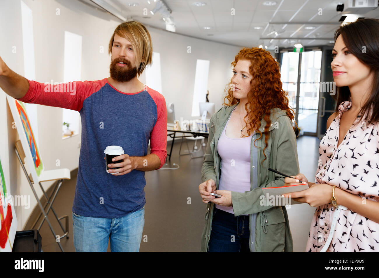 Young people standing in a gallery and contemplating abstract artwork ...