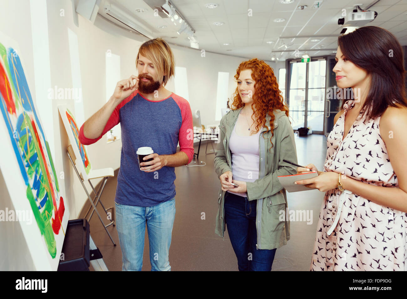 Young people standing in a gallery and contemplating abstract artwork ...