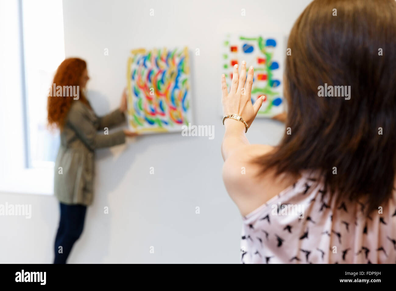 Young artists in gallery hanging together painting on walls Stock Photo ...