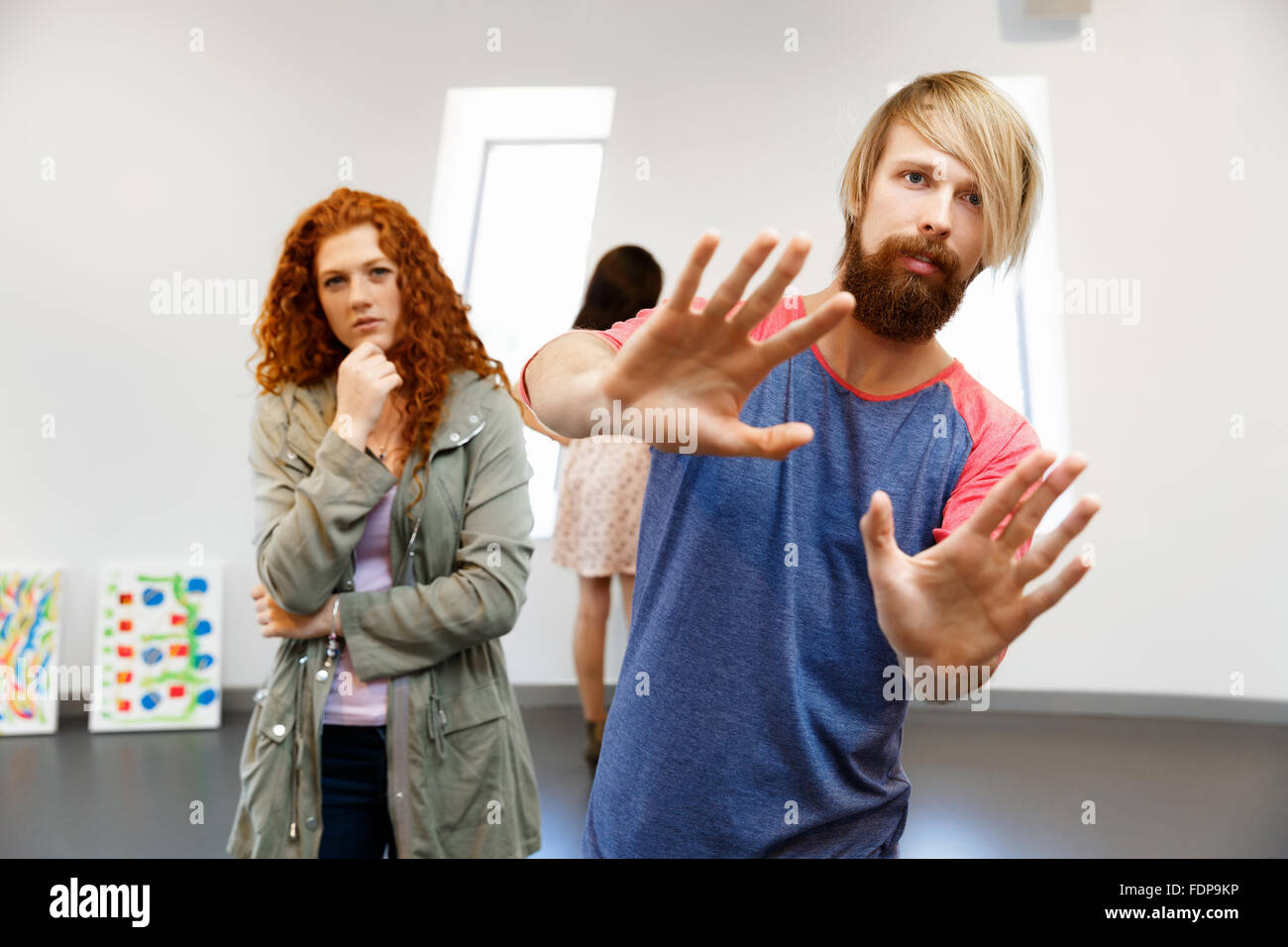 Young artists in gallery hanging together painting on walls Stock Photo ...