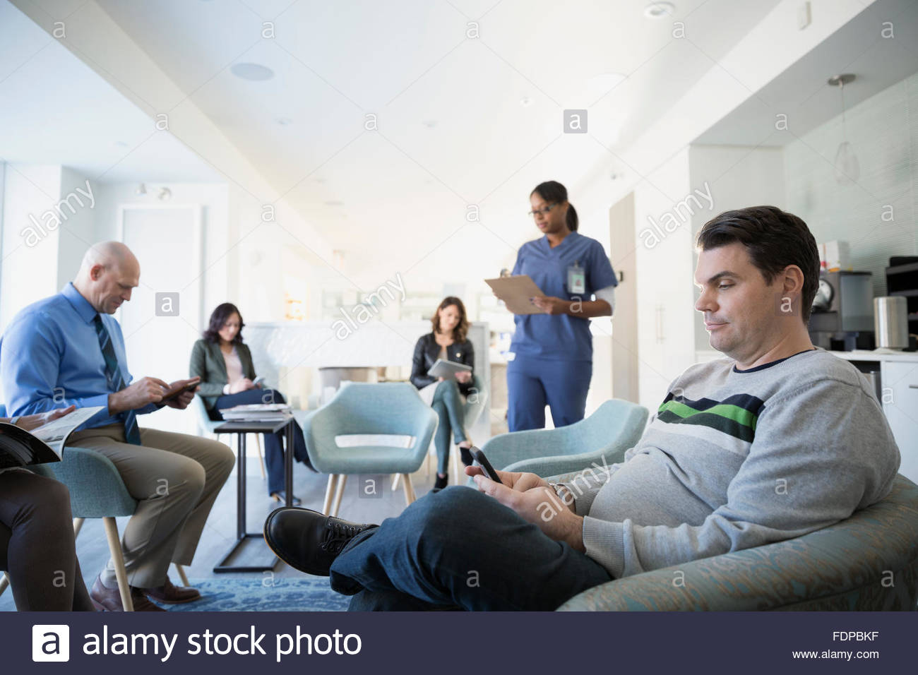 Man texting waiting in clinic lobby Stock Photo - Alamy