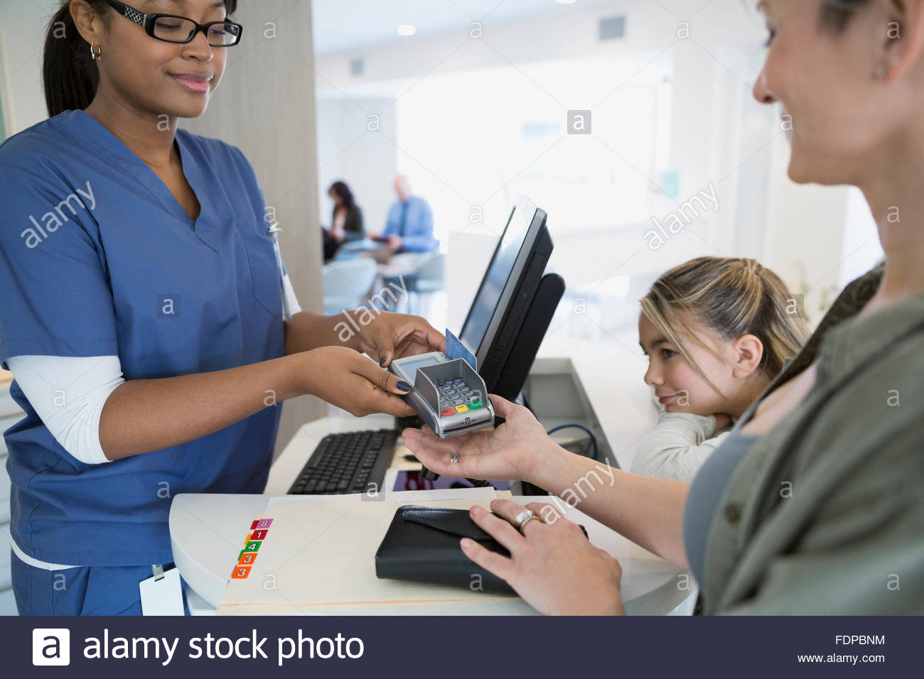 Nurse handing credit card reader to patient clinic Stock Photo - Alamy