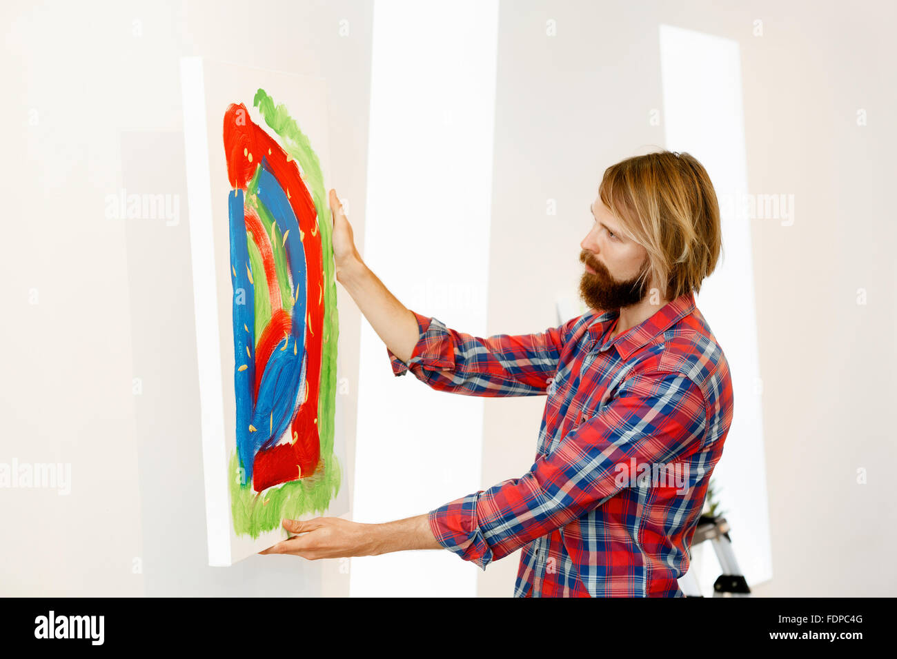 Young male artist standing with his picture Stock Photo - Alamy