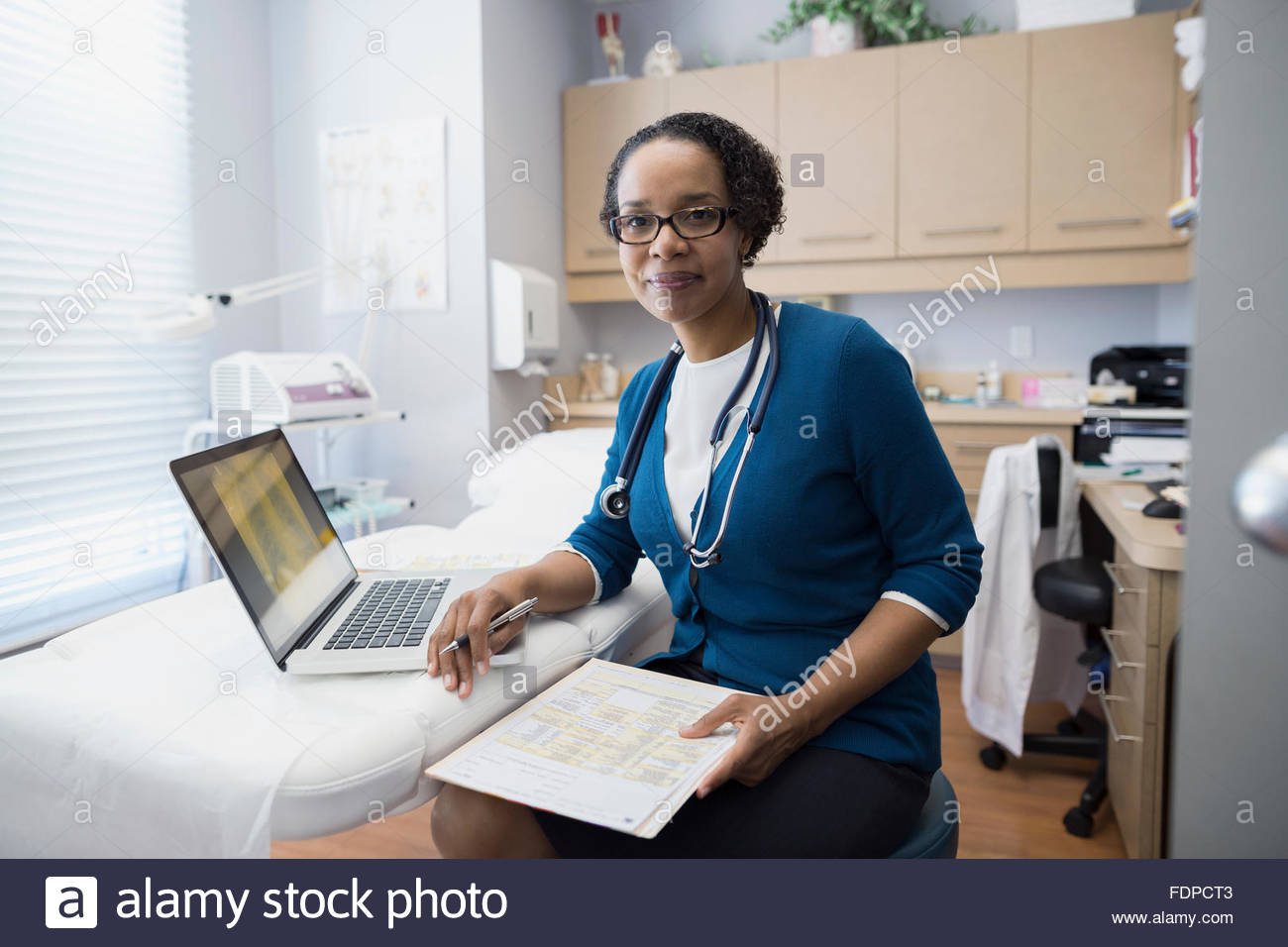 Portrait confident doctor working at laptop examination room Stock ...