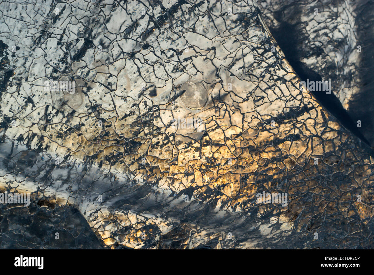Frozen ice patterns with light filtering through the cracks. The ...