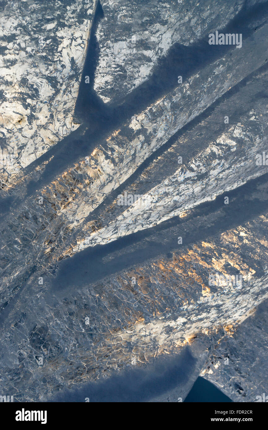 Frozen ice patterns with light filtering through the cracks. The ...