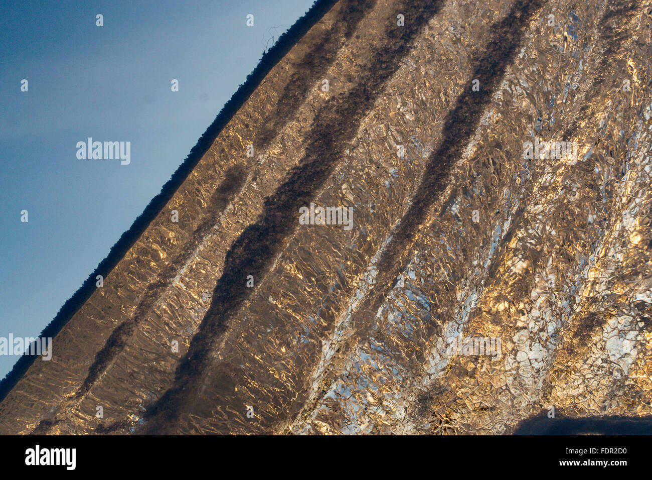 Frozen ice patterns with light filtering through the cracks. The ...