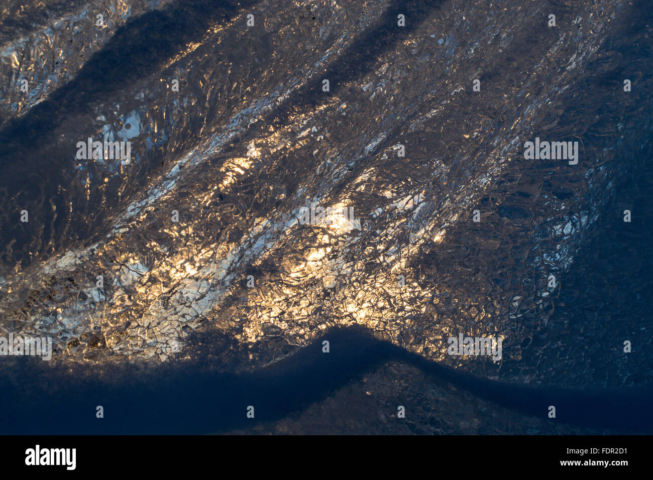 Frozen ice patterns with light filtering through the cracks. The ...