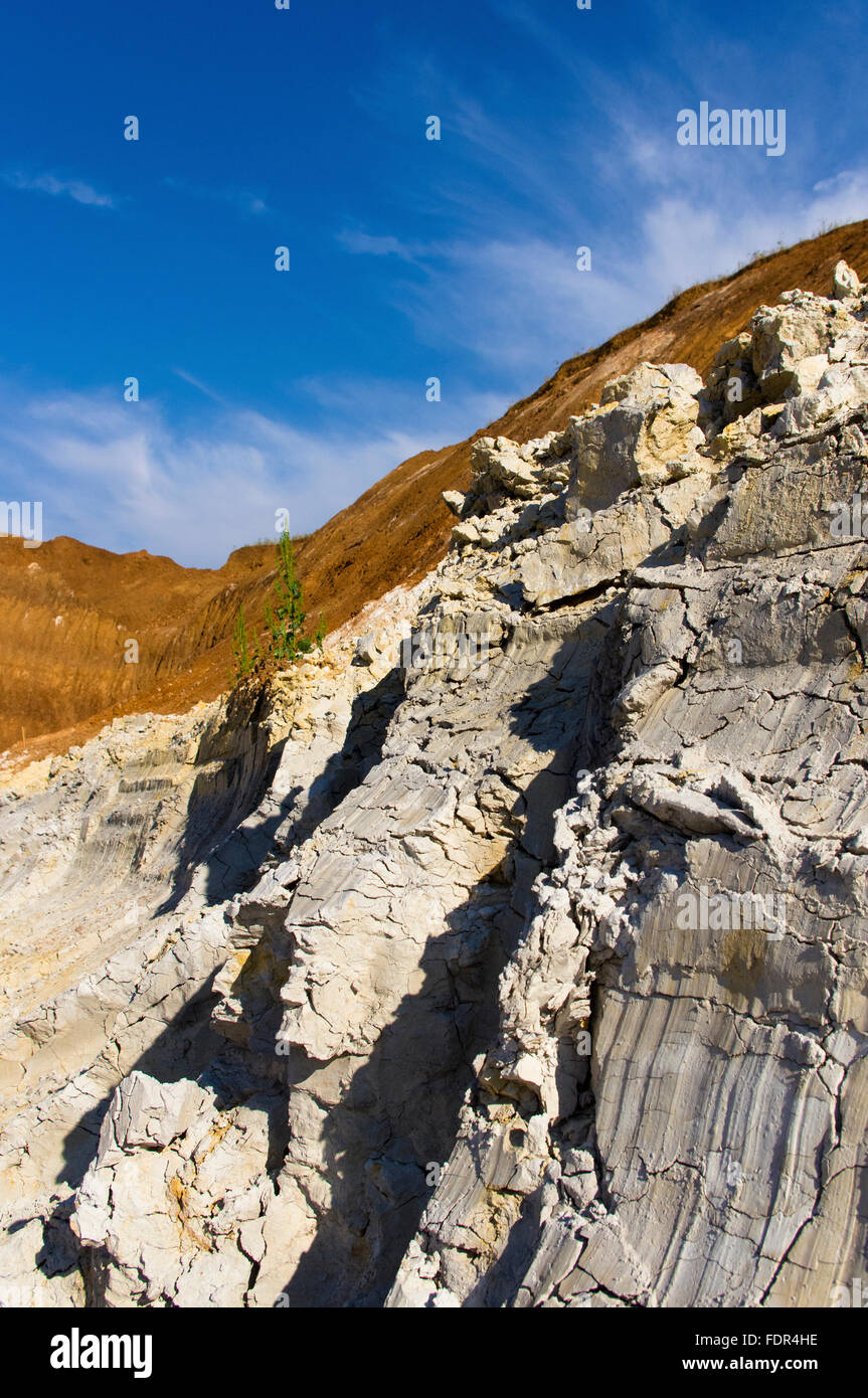 clay quarry with traces of the excavator bucket on blue sky background ...