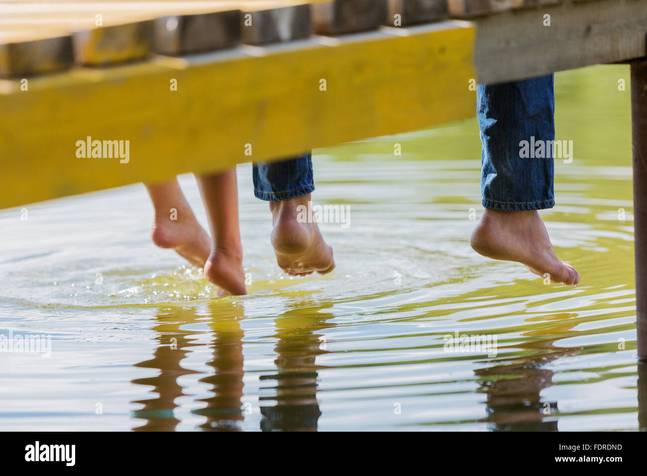Close up of people's feet sitting on bridge Stock Photo - Alamy