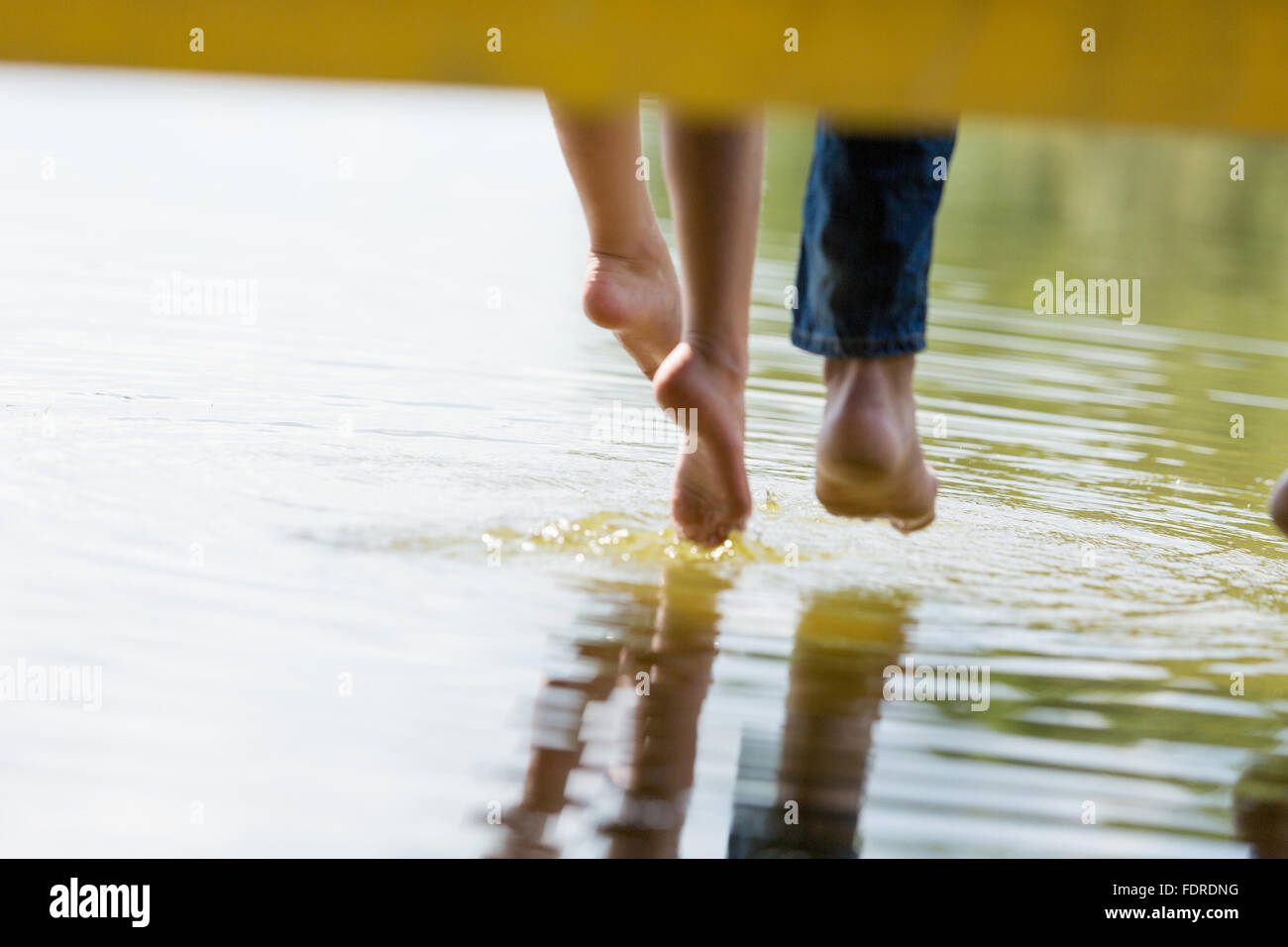 Close up of people's feet sitting on bridge Stock Photo - Alamy