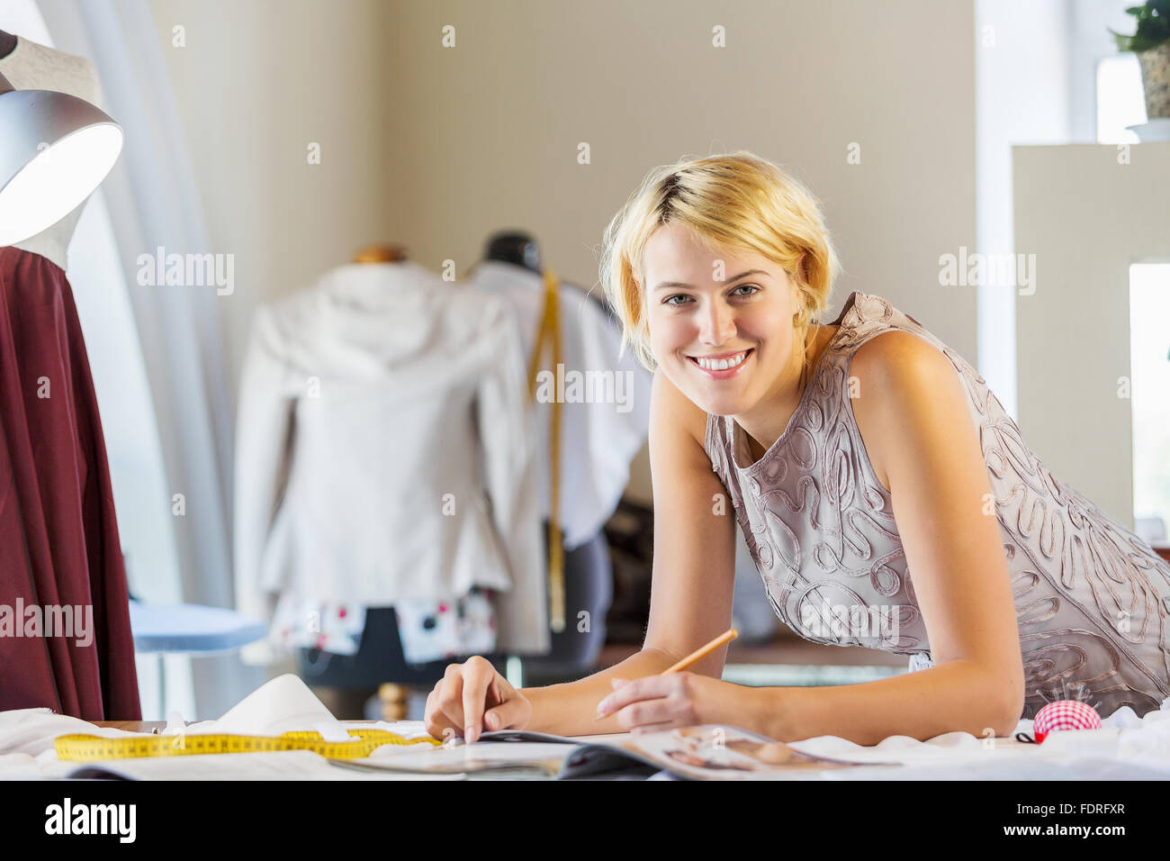 Pretty dressmaker at work making patterns of fabric Stock Photo - Alamy