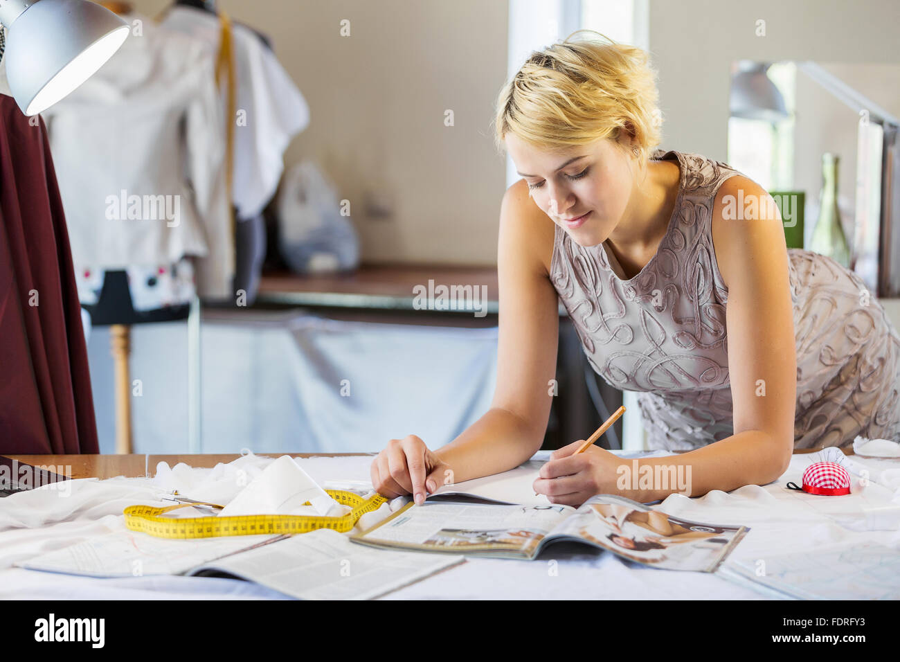 Pretty dressmaker at work making patterns of fabric Stock Photo - Alamy