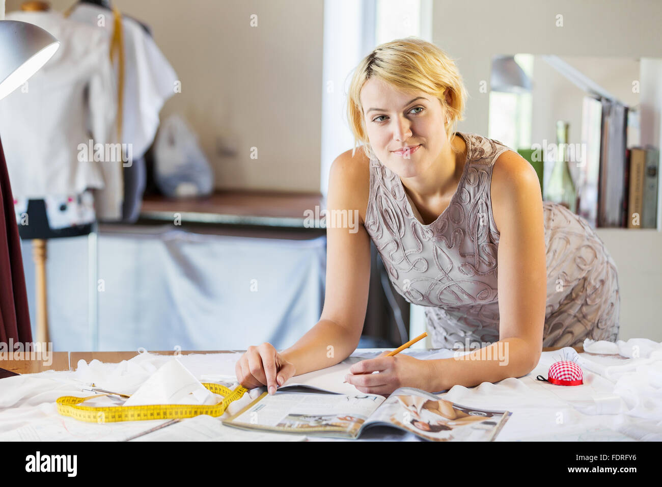 Pretty dressmaker at work making patterns of fabric Stock Photo - Alamy