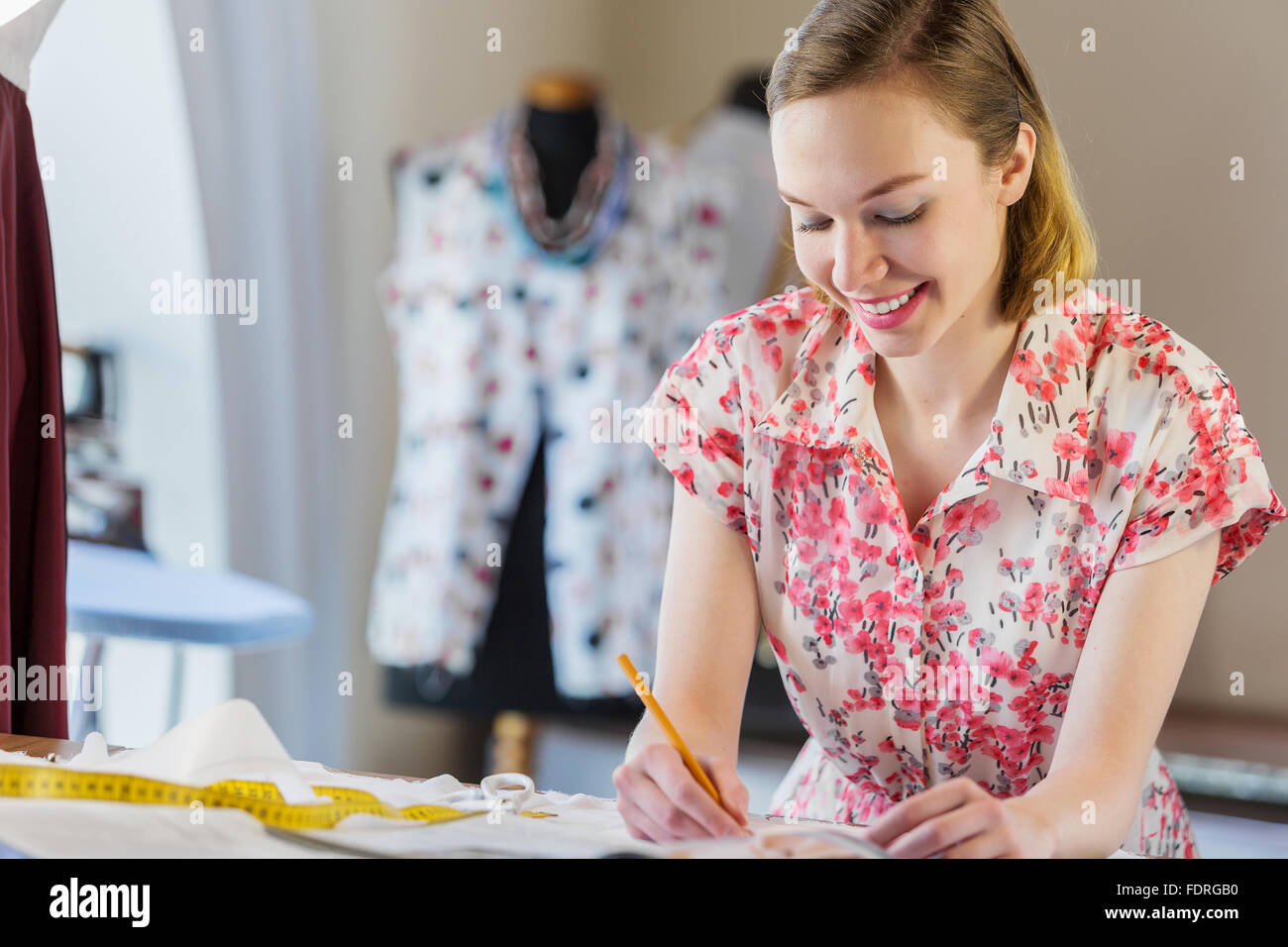 Pretty dressmaker at work making patterns of fabric Stock Photo - Alamy