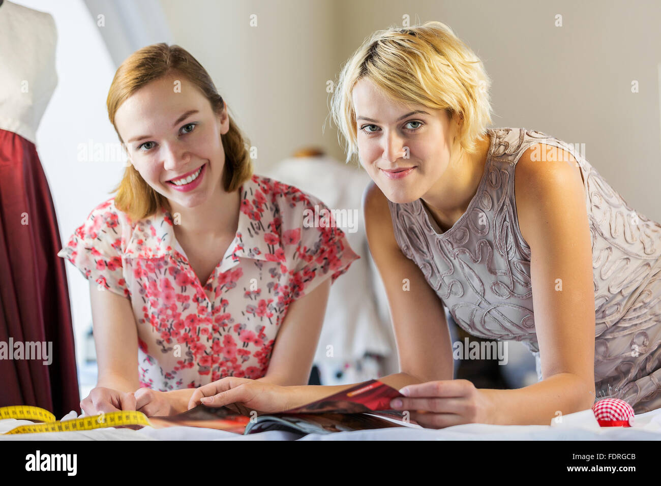 Two attractive women at dressmakers choosing design Stock Photo - Alamy