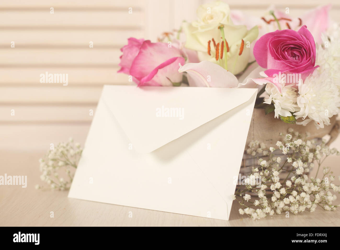 Basket of flowers and blank envelope on wooden background Stock Photo ...