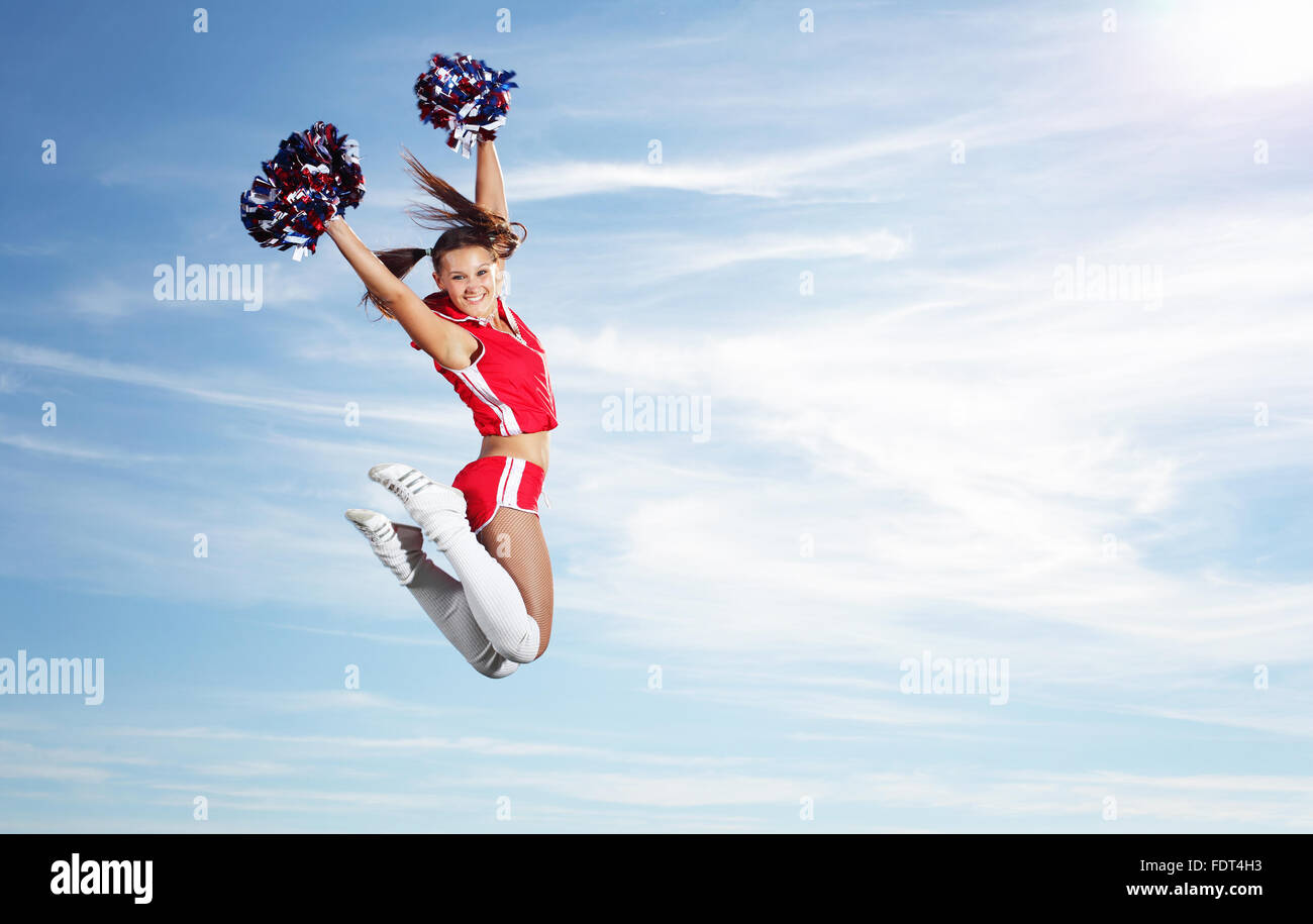 Young beautiful female cheerleader in uniform jumping high Stock Photo ...