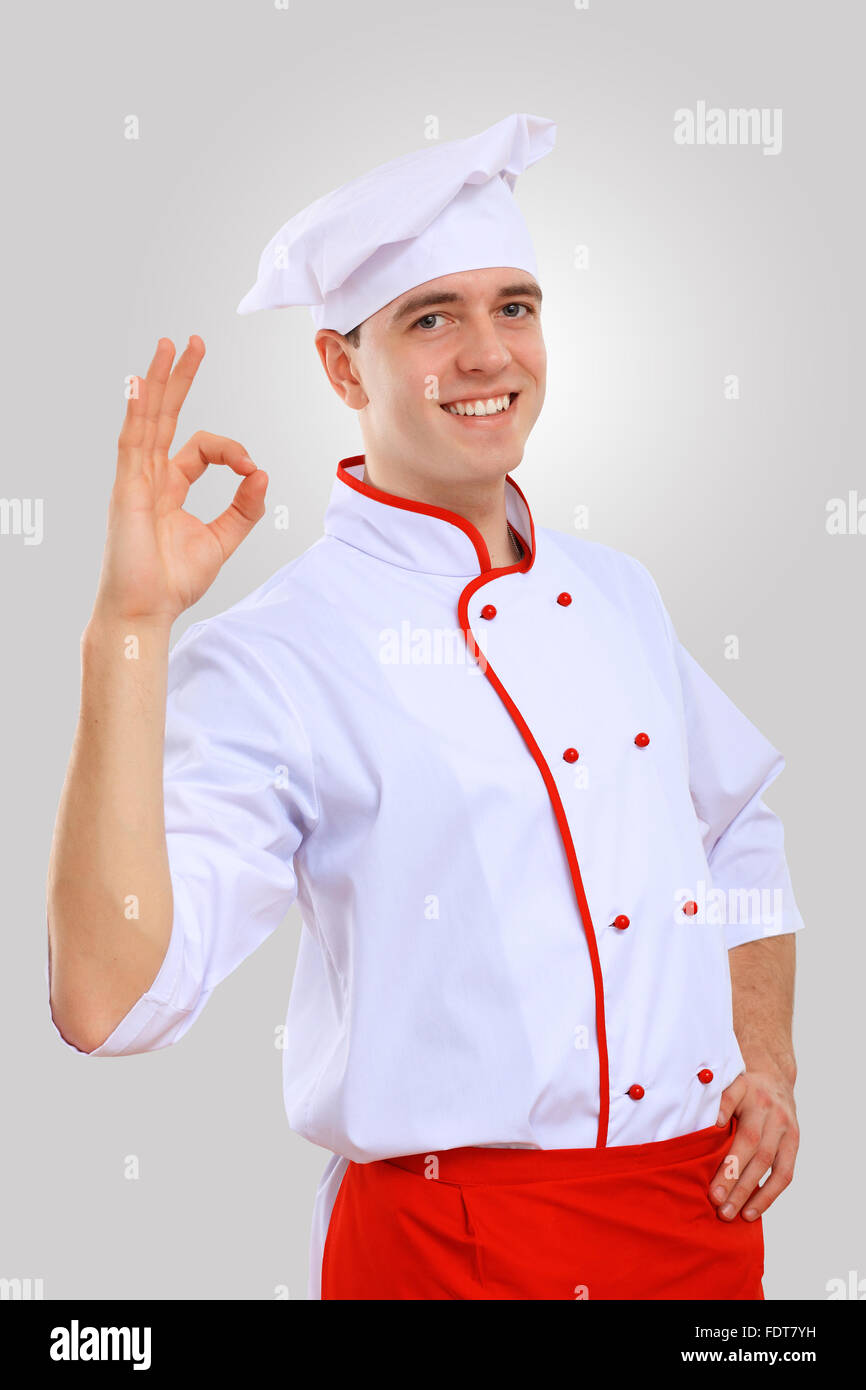Young male chef in red apron against grey background Stock Photo - Alamy