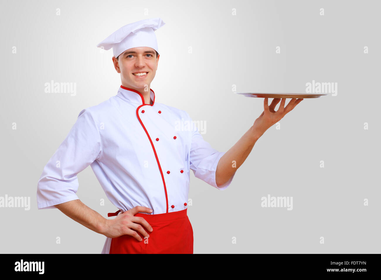 Young male chef in red apron against grey background Stock Photo - Alamy