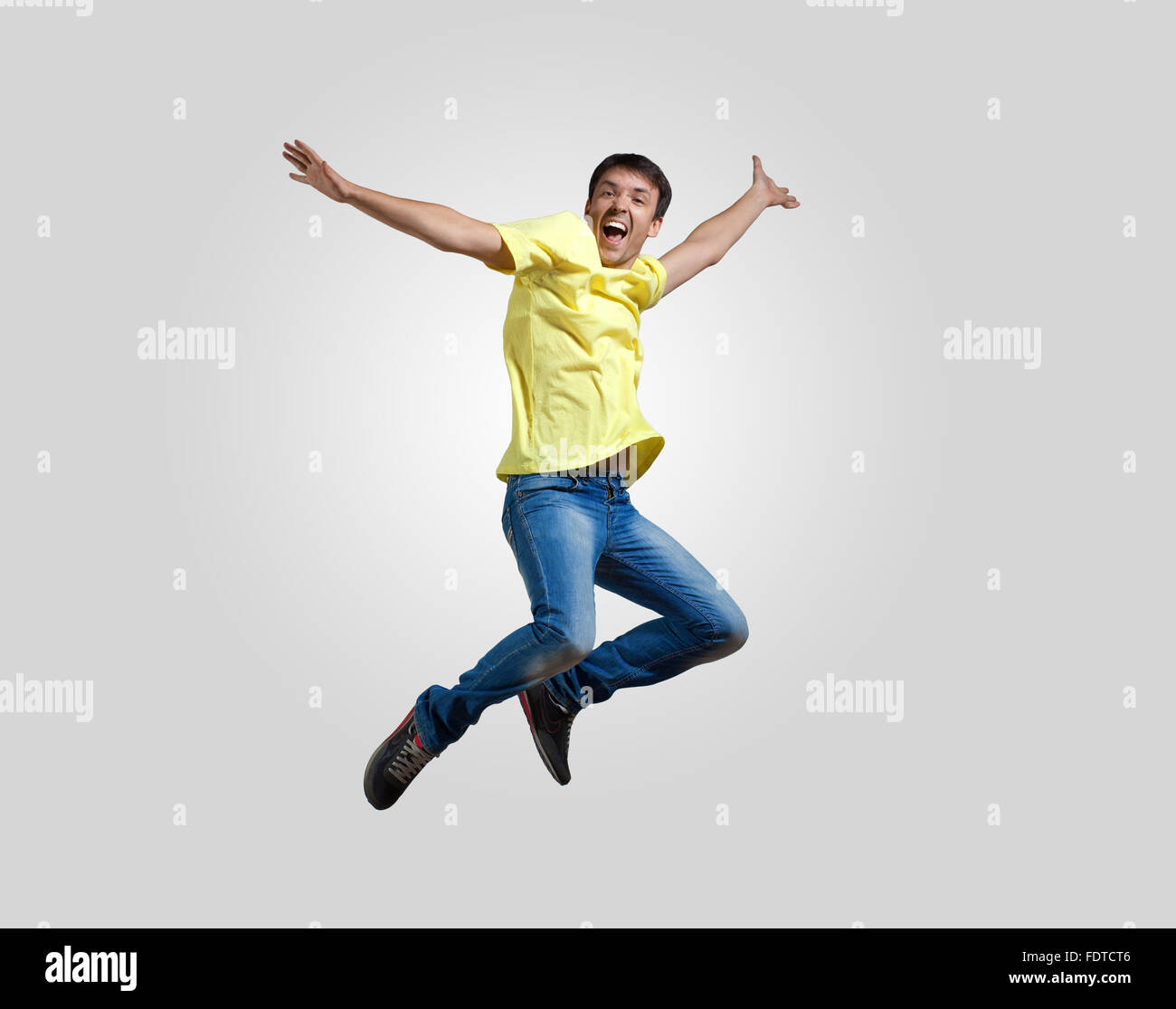 Modern slim hip-hop style man jumping dancing on a grey background ...