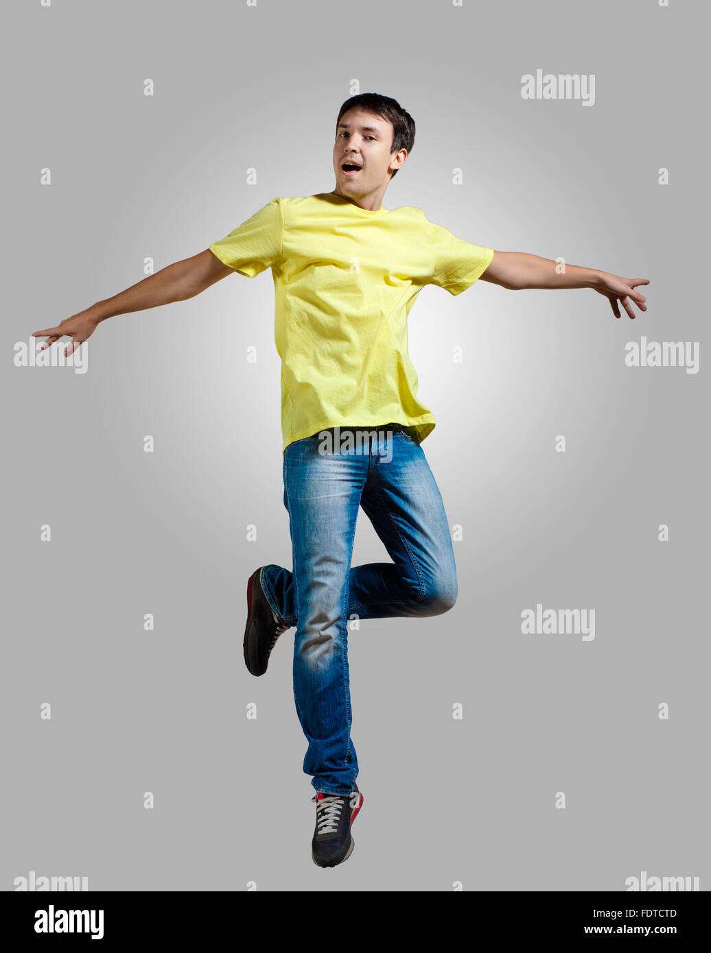 Modern slim hip-hop style man jumping dancing on a grey background ...