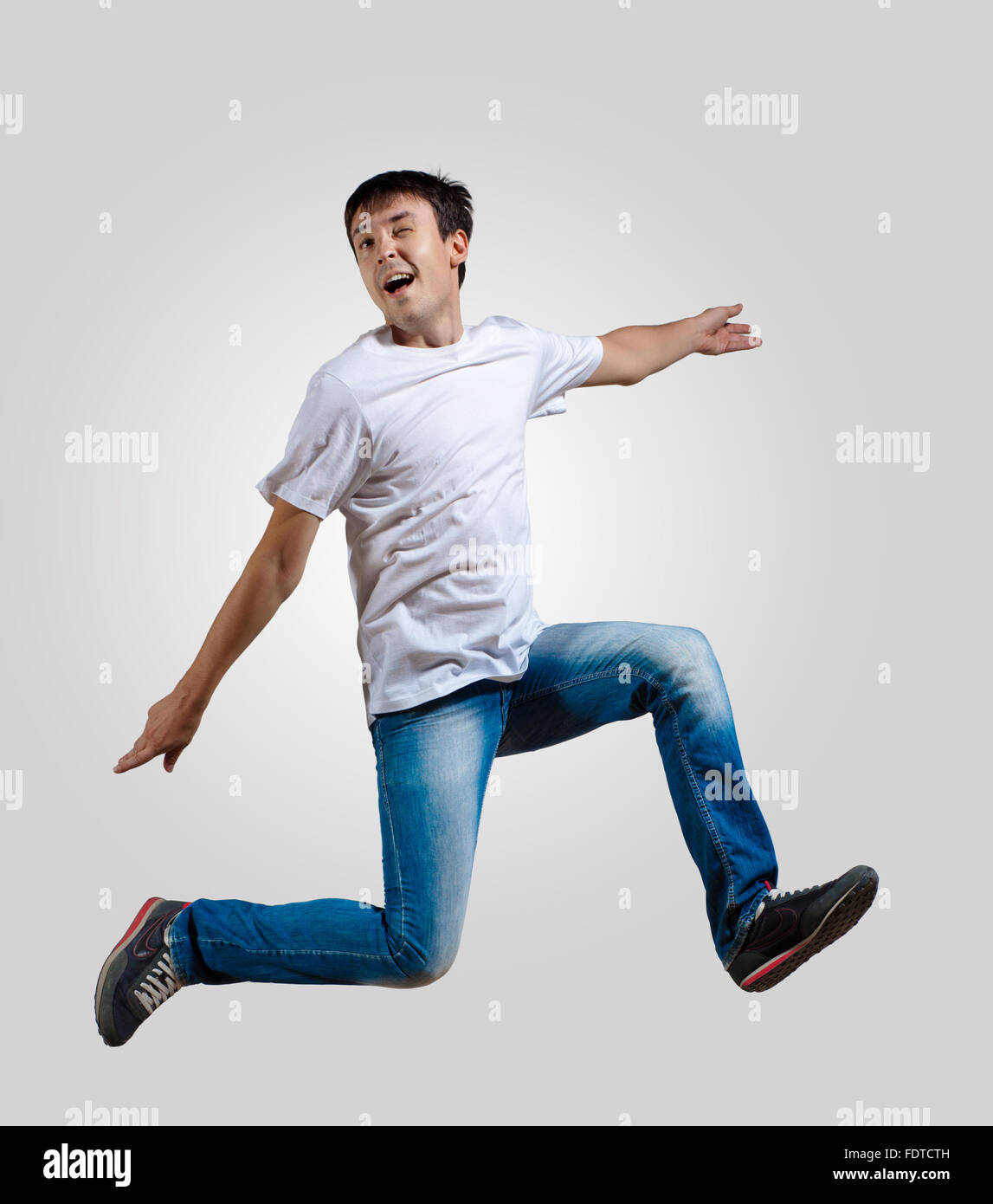 Modern slim hip-hop style man jumping dancing on a grey background ...