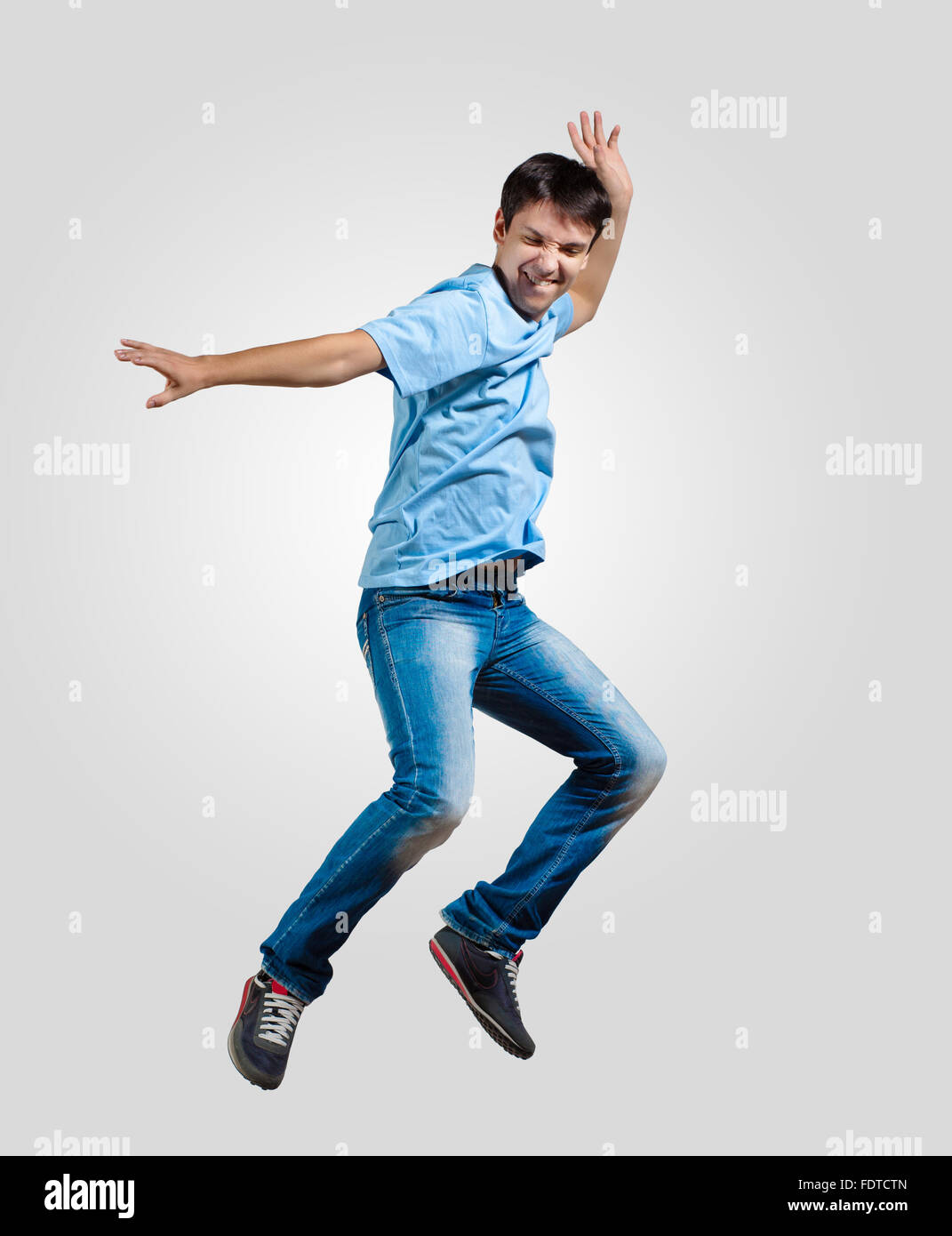 Modern slim hip-hop style man jumping dancing on a grey background ...