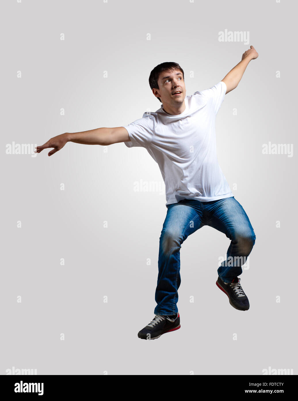 Modern slim hip-hop style man jumping dancing on a grey background ...