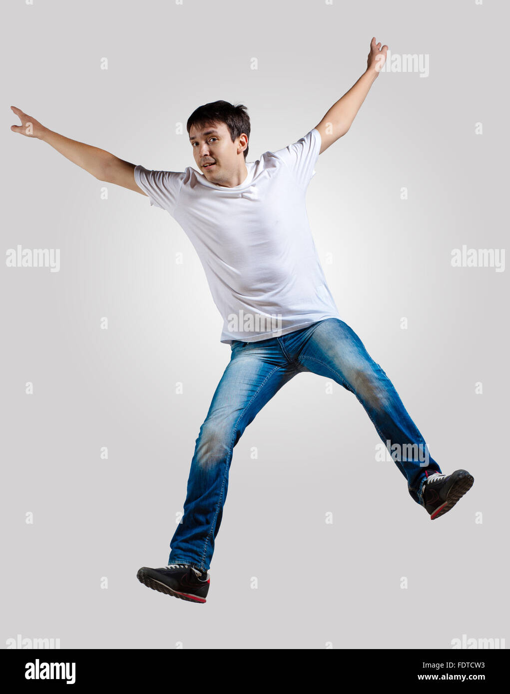 Modern slim hip-hop style man jumping dancing on a grey background ...
