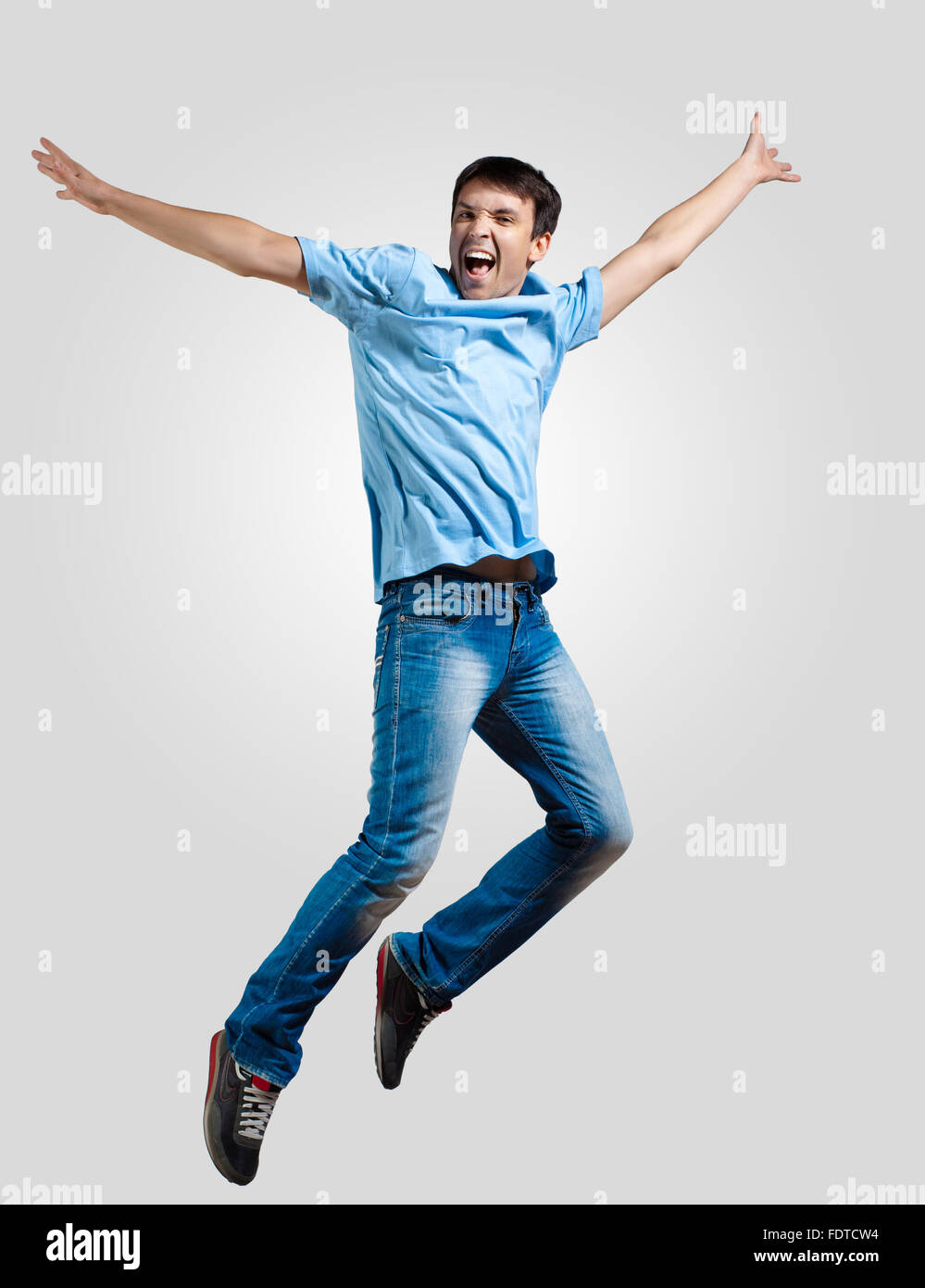 Modern slim hip-hop style man jumping dancing on a grey background ...