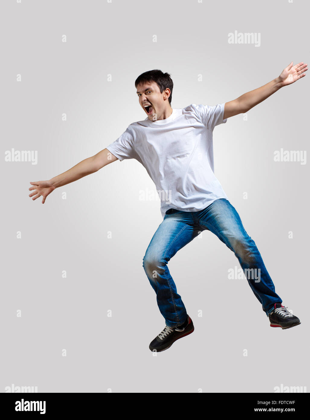 Modern slim hip-hop style man jumping dancing on a grey background ...