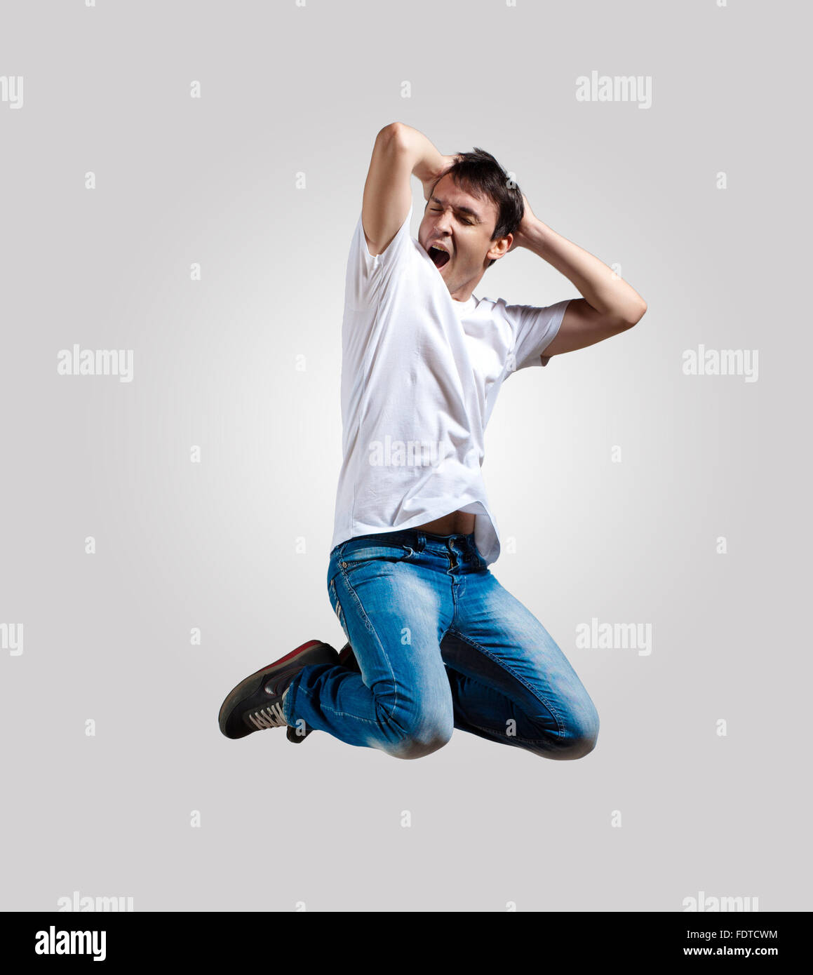 Modern slim hip-hop style man jumping dancing on a grey background ...