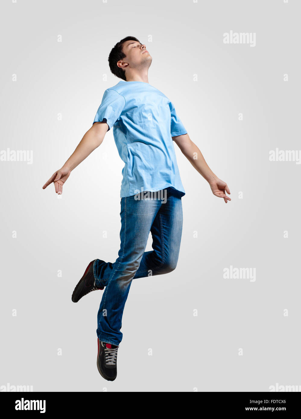Modern slim hip-hop style man jumping dancing on a grey background ...