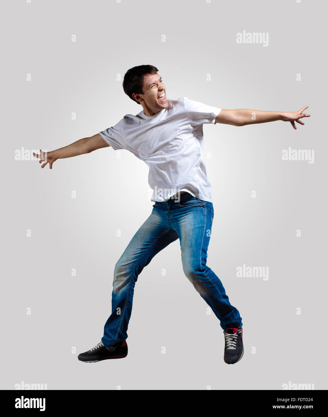 Modern slim hip-hop style man jumping dancing on a grey background ...