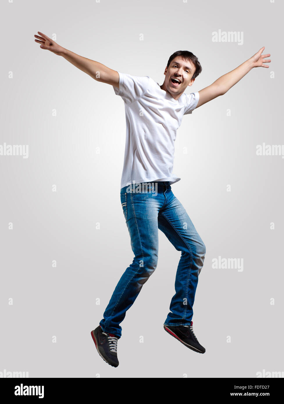 Modern slim hip-hop style man jumping dancing on a grey background ...