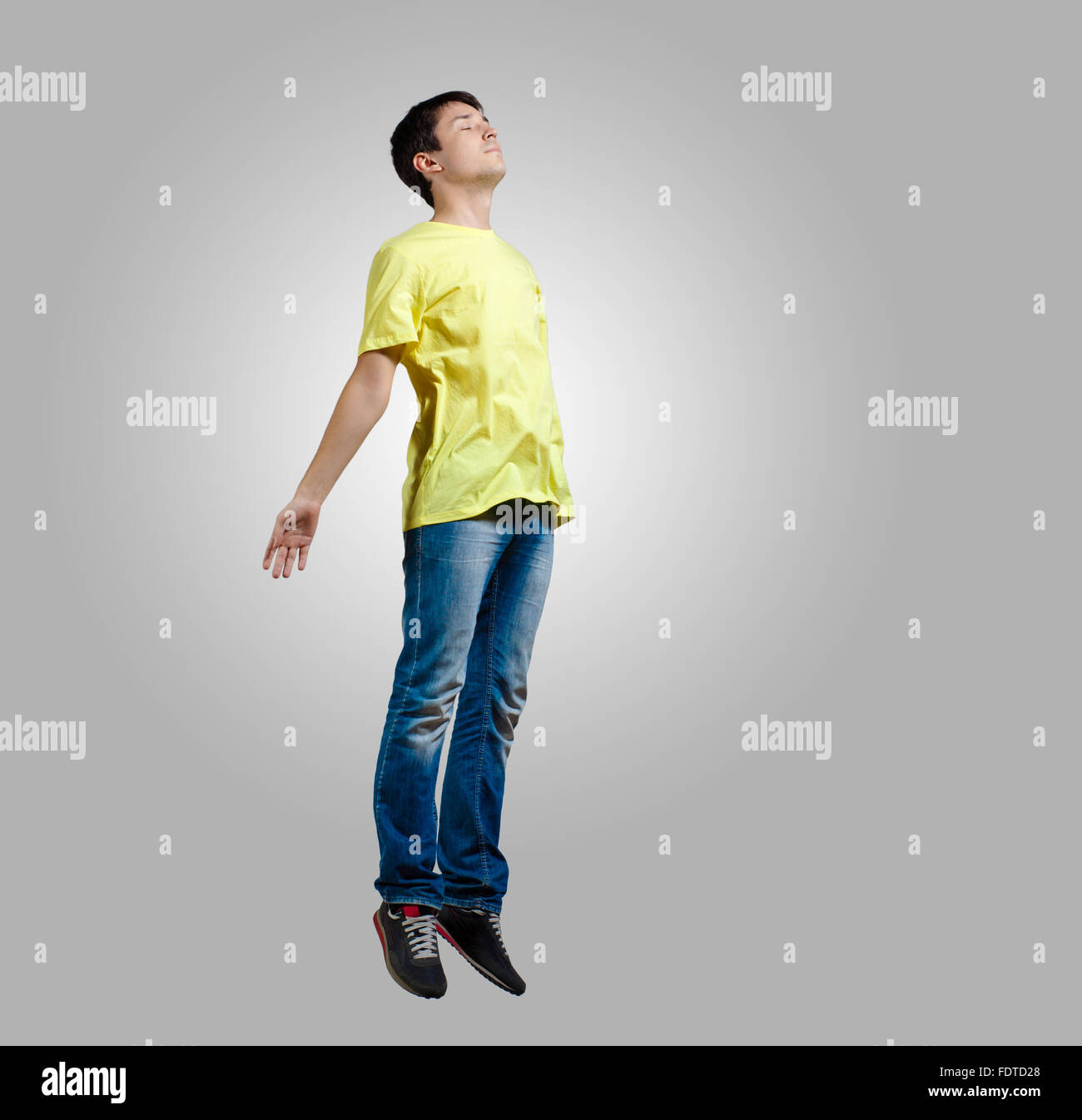 Modern slim hip-hop style man jumping dancing on a grey background ...
