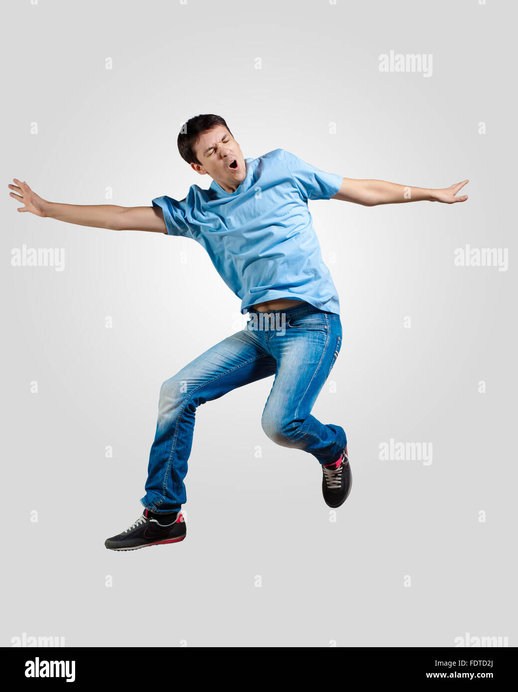 Modern slim hip-hop style man jumping dancing on a grey background ...