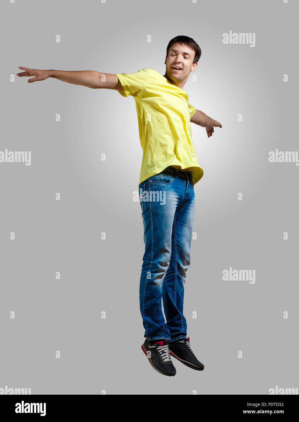 Modern slim hip-hop style man jumping dancing on a grey background ...