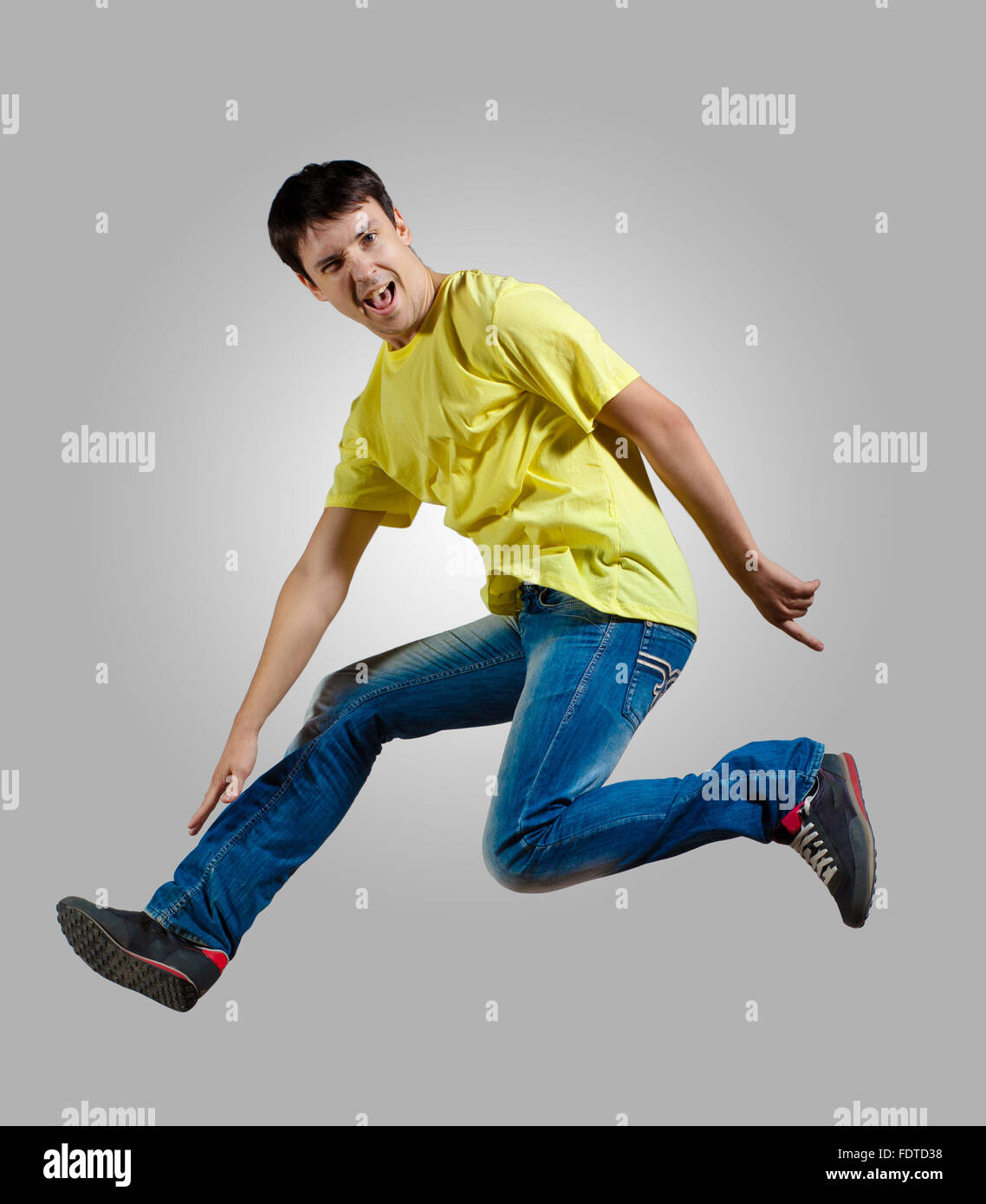 Modern slim hip-hop style man jumping dancing on a grey background ...