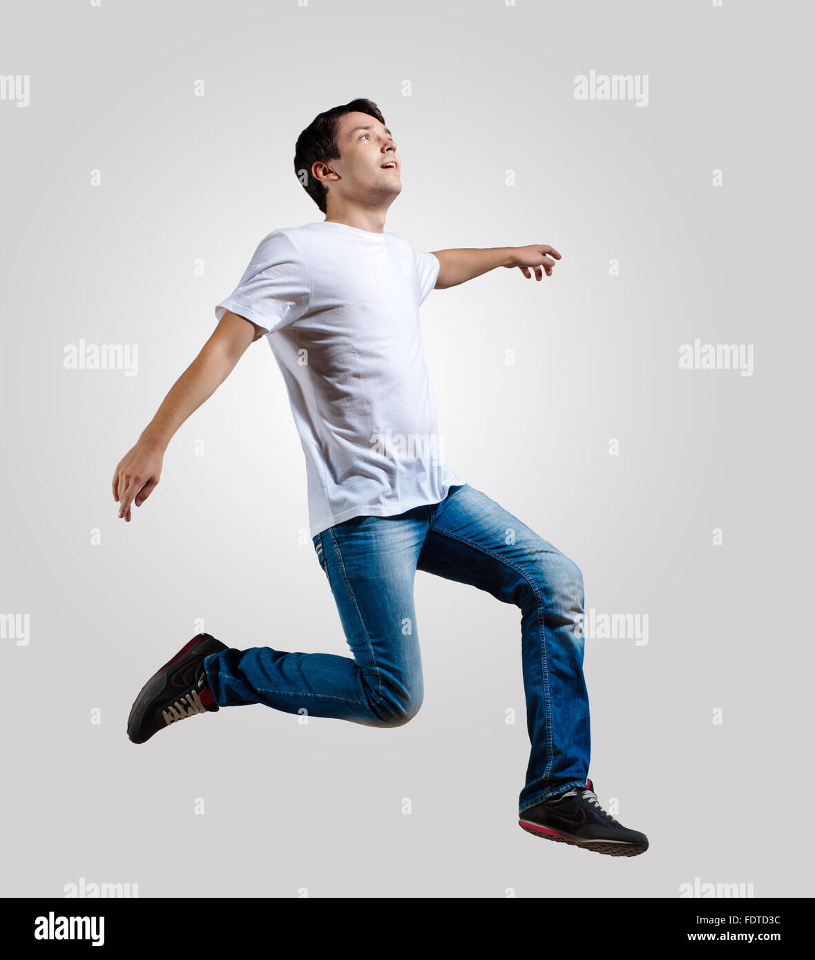 Modern slim hip-hop style man jumping dancing on a grey background ...
